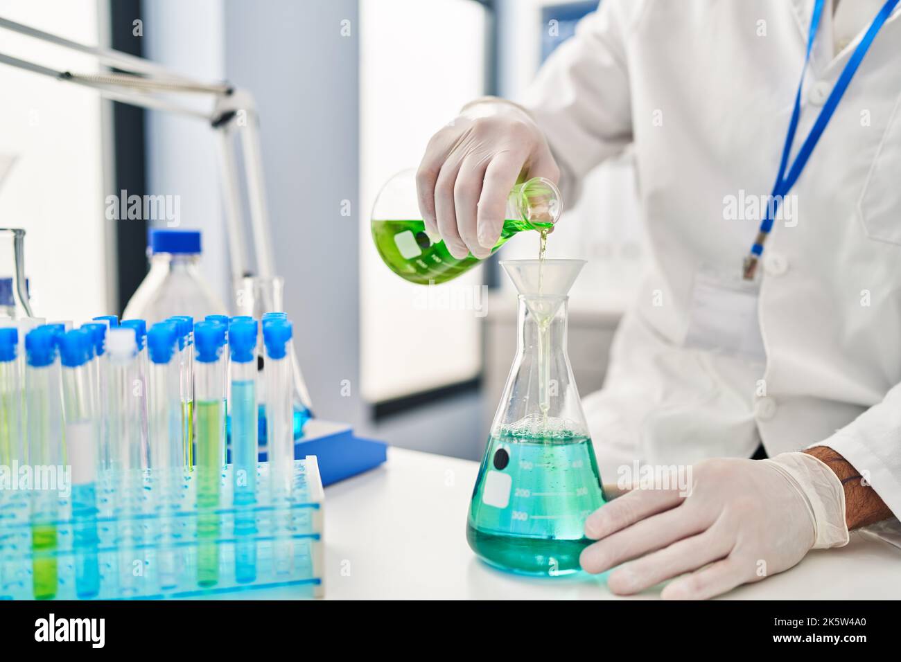 Young hispanic man scientist measuring liquid at laboratory Stock Photo ...