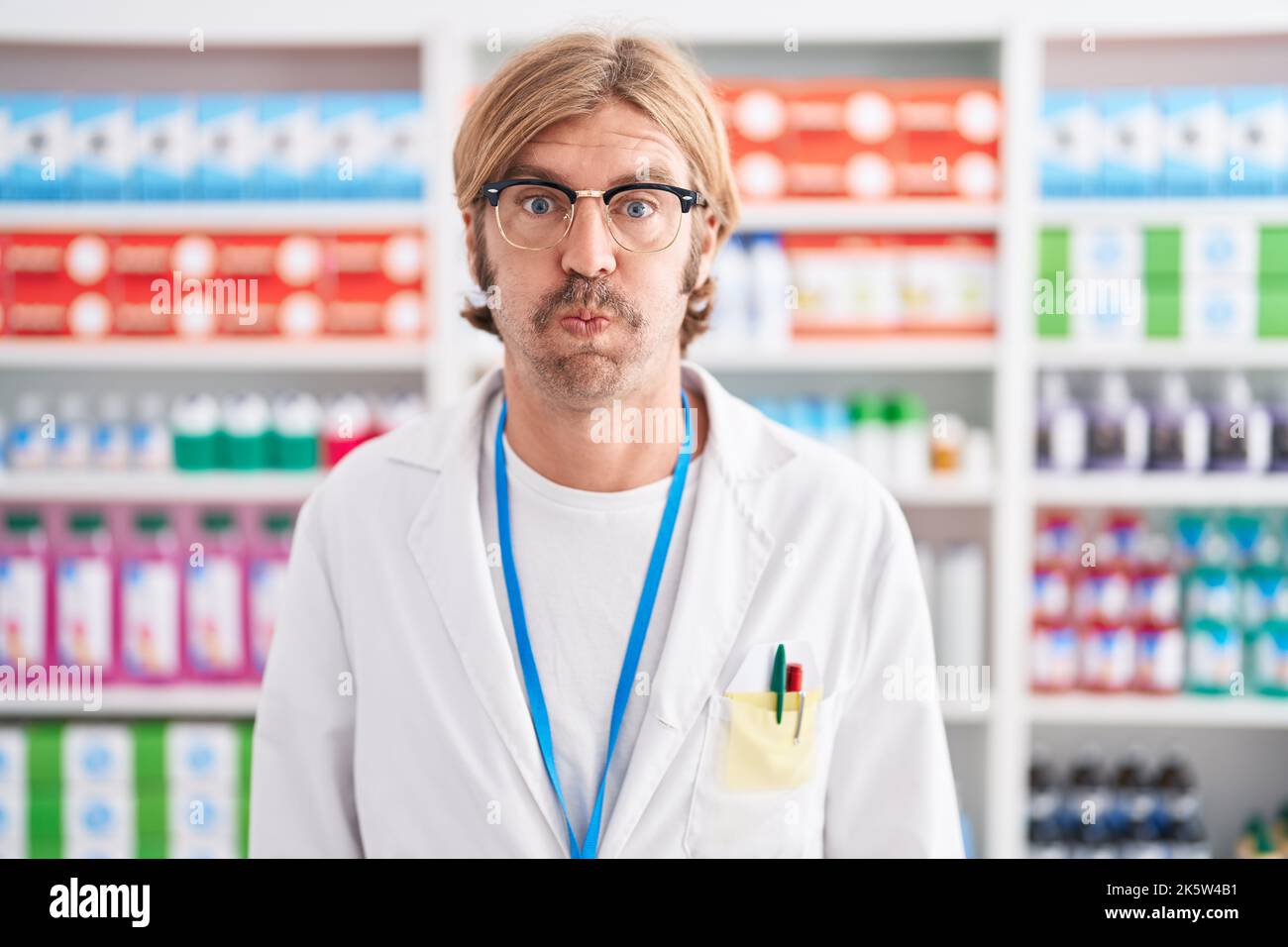 Caucasian man with mustache working at pharmacy drugstore puffing ...