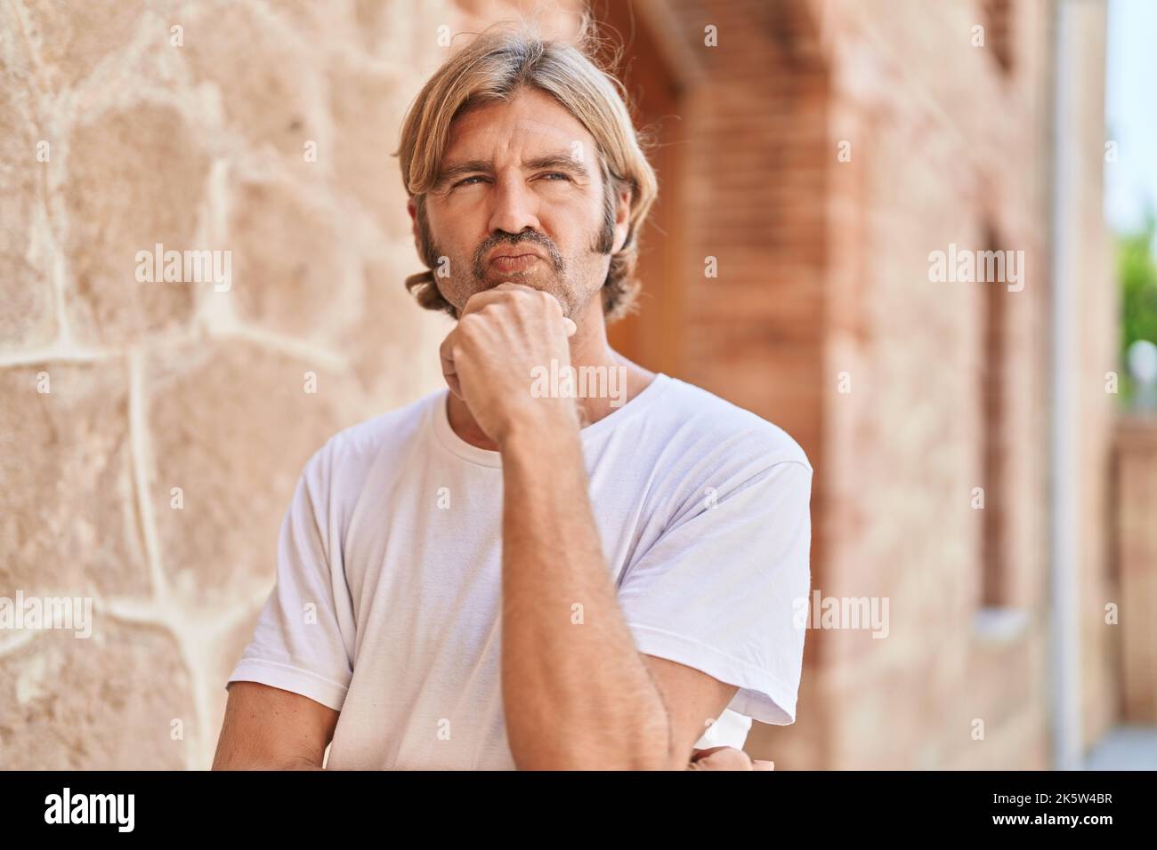 Young blond man standing with doubt expression at street Stock Photo ...