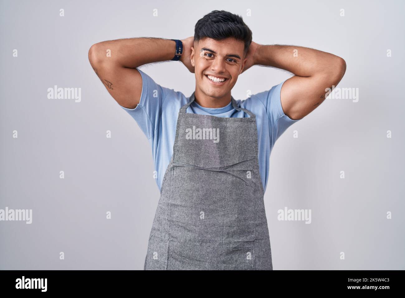 Hispanic young man wearing apron over white background relaxing and ...