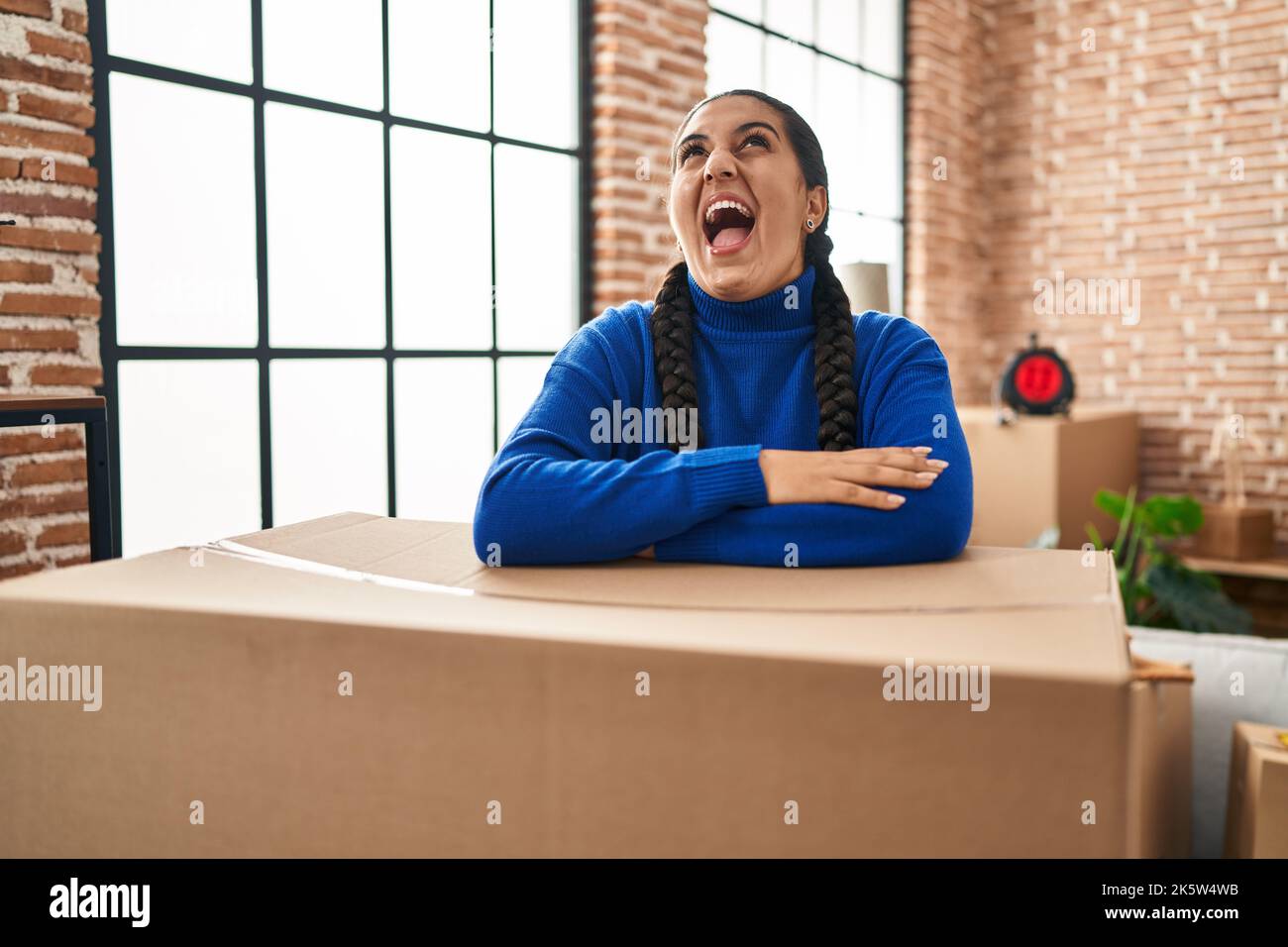 Young hispanic woman moving to a new home angry and mad screaming ...