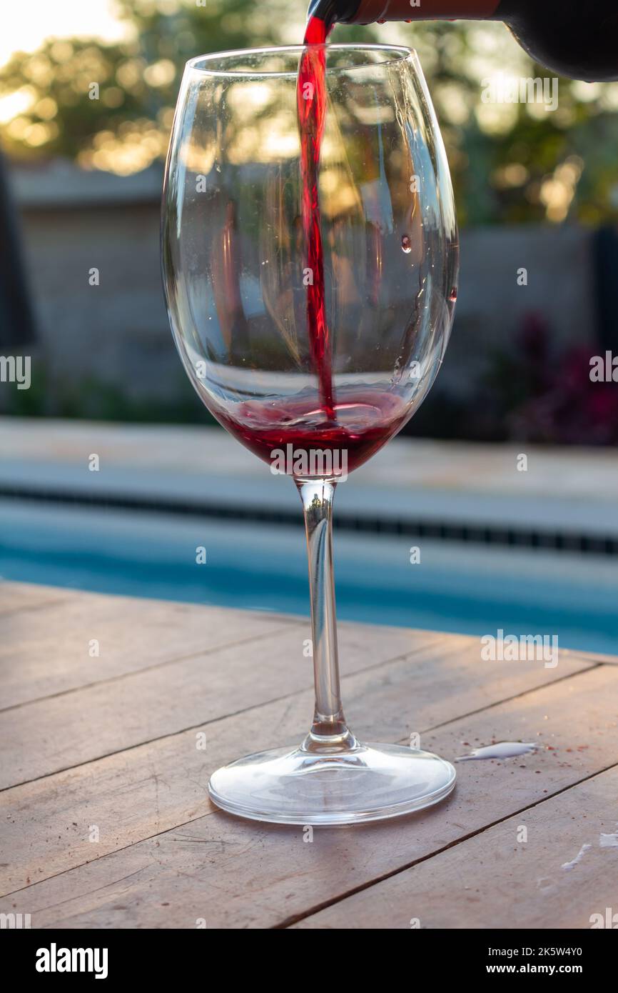 Large crystal glass into which red wine is poured. High class pool ...