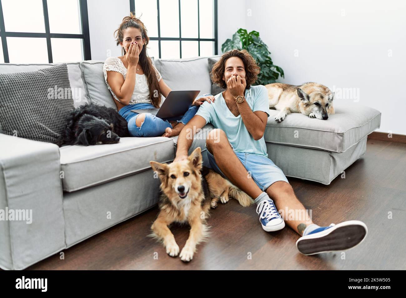 Young hispanic couple with dogs relaxing at home laughing and ...