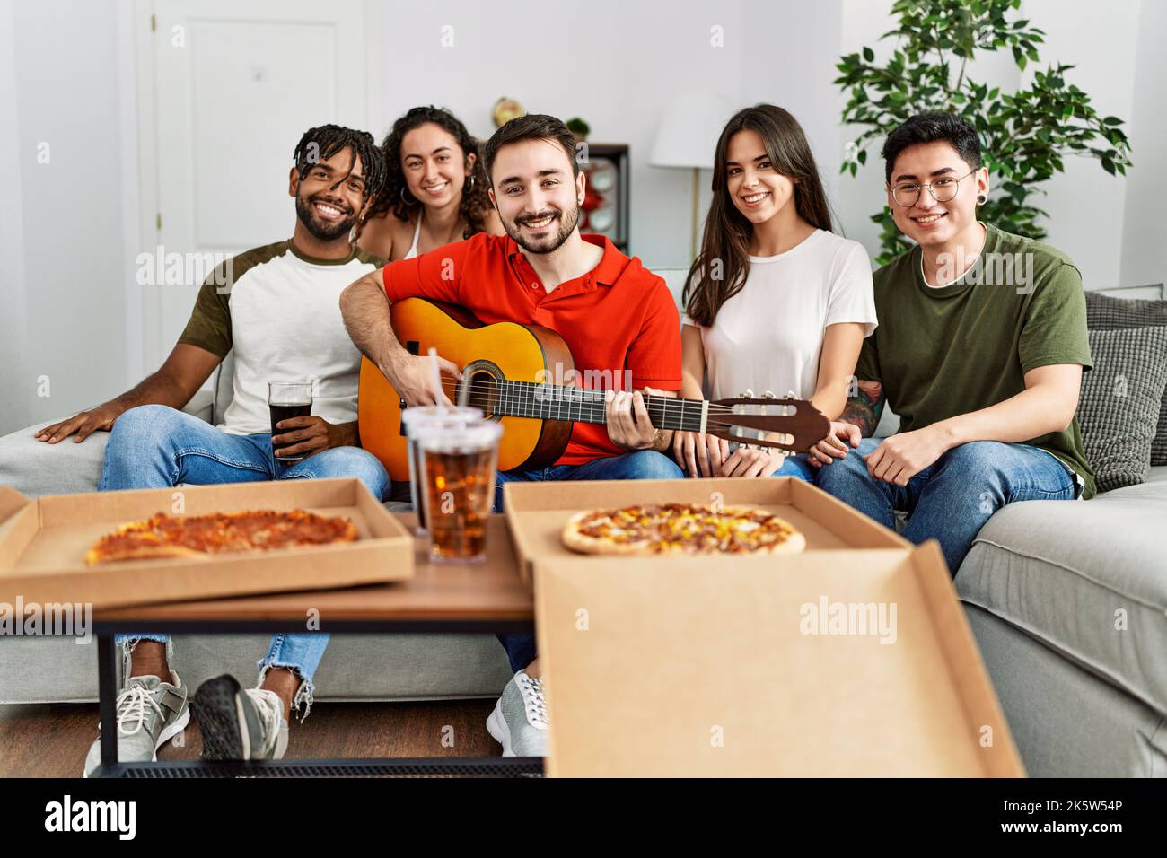 Group of young friends having party eating italian pizza and playing ...