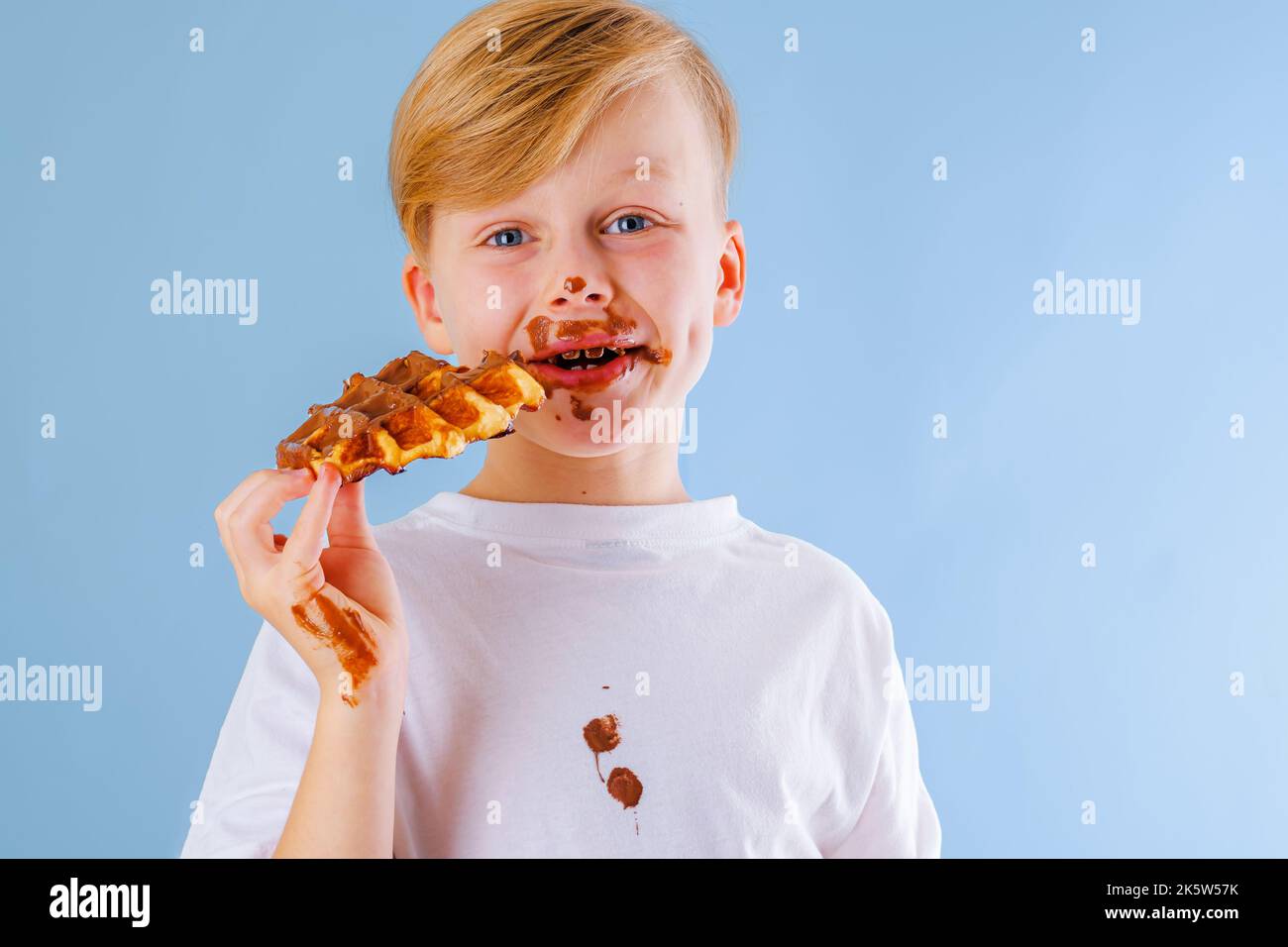 The child is eating Belgian waffle with chocolate sauce on a blue ...