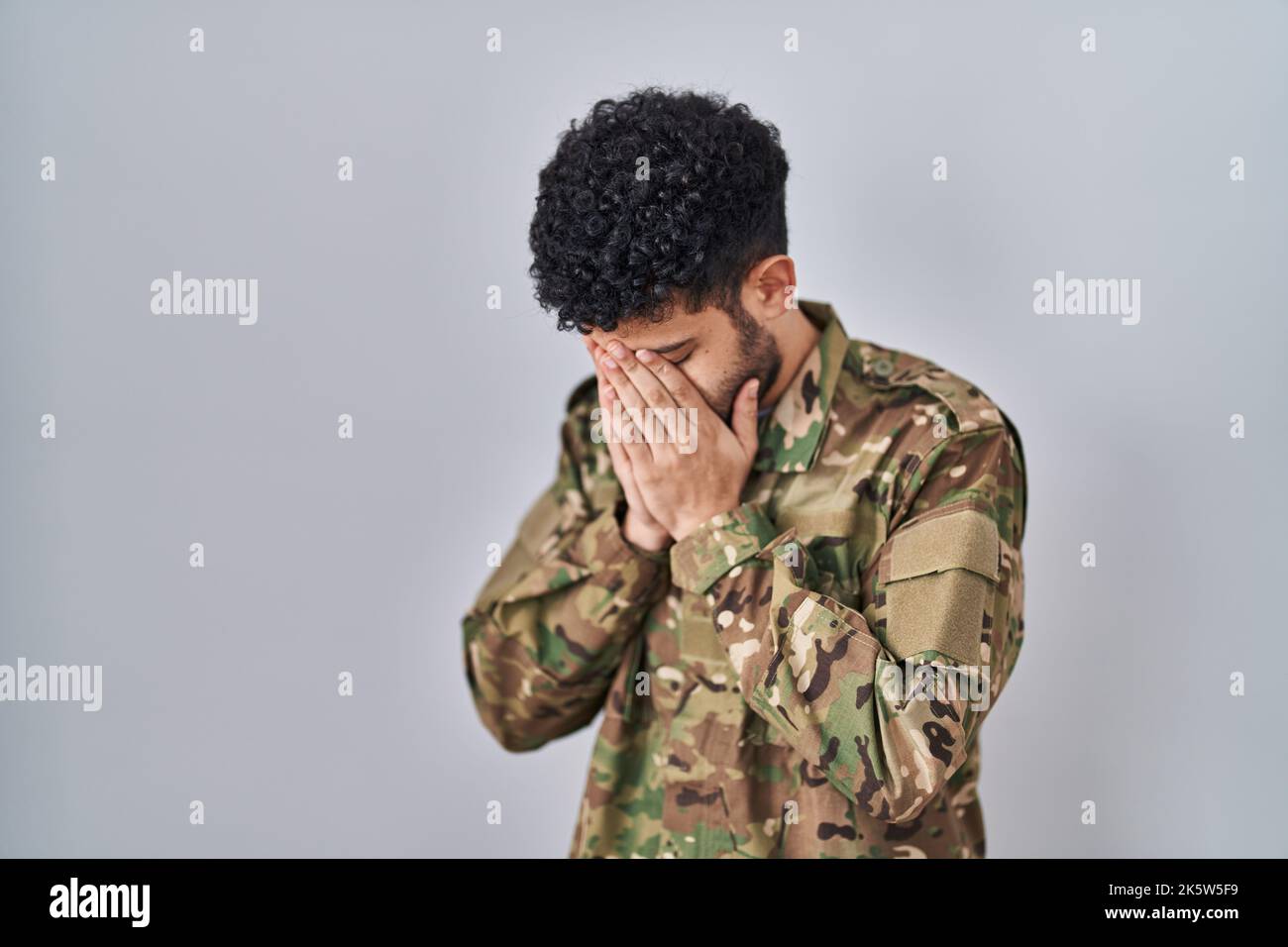 Arab man wearing camouflage army uniform with sad expression covering ...