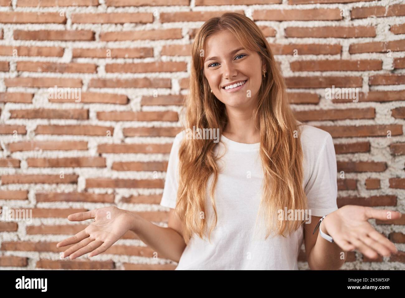 Young caucasian woman standing over bricks wall smiling cheerful with ...