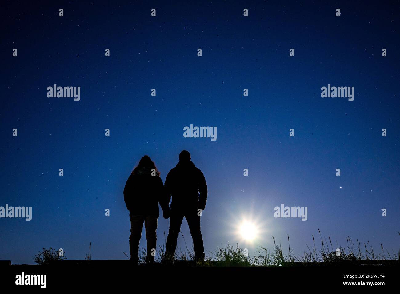 Romantic couple watching the moon rise up at Hansweert The Netherlands ...