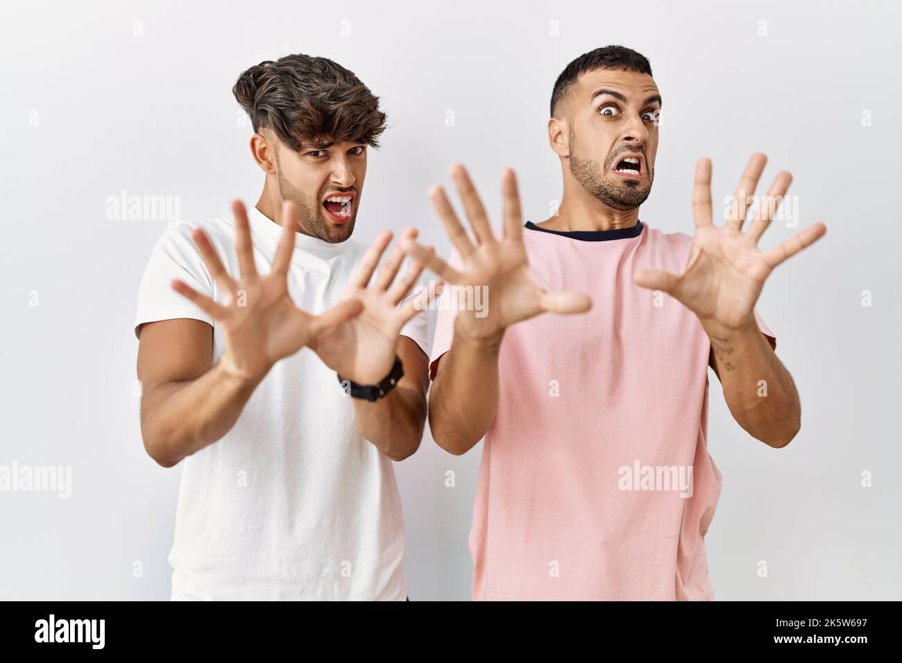 Young gay couple standing over isolated background afraid and terrified ...