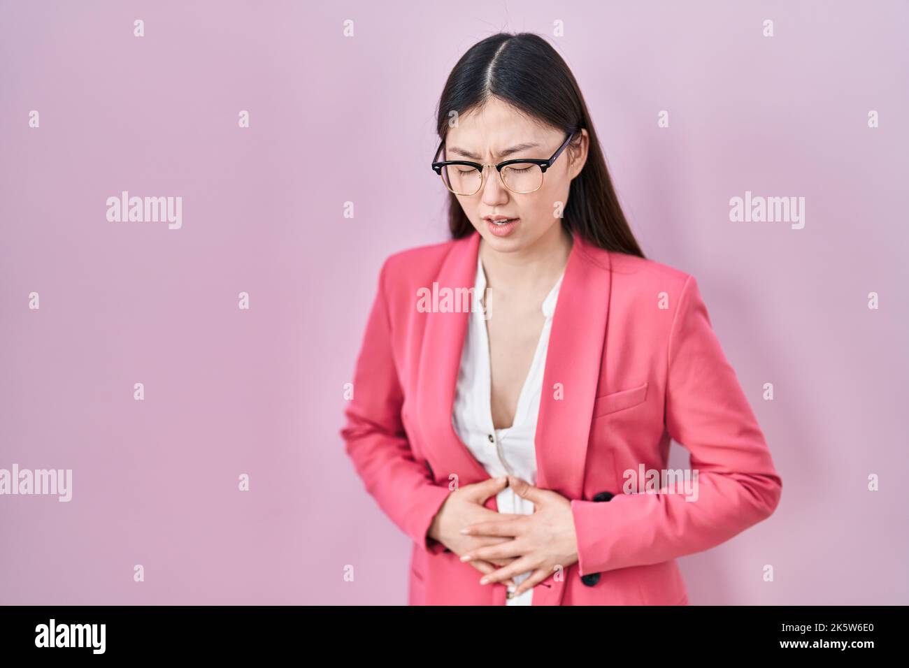 Chinese business young woman wearing glasses with hand on stomach ...