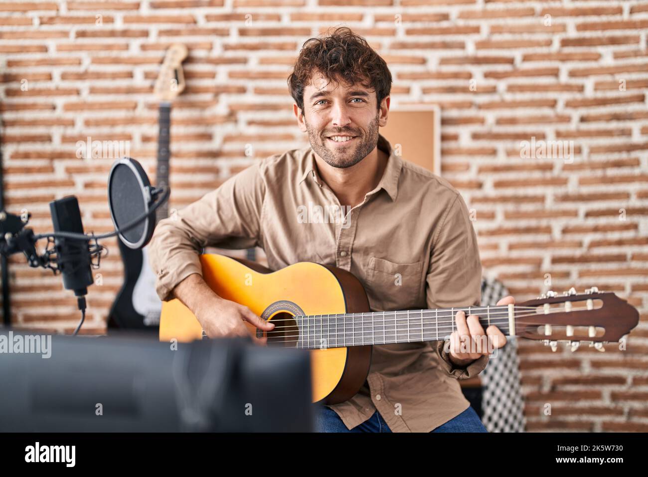Young man musician smiling confident playing classical guitar at music ...