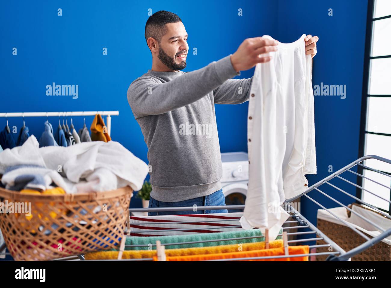 Young latin man smiling confident hanging clothes on clothesline at ...