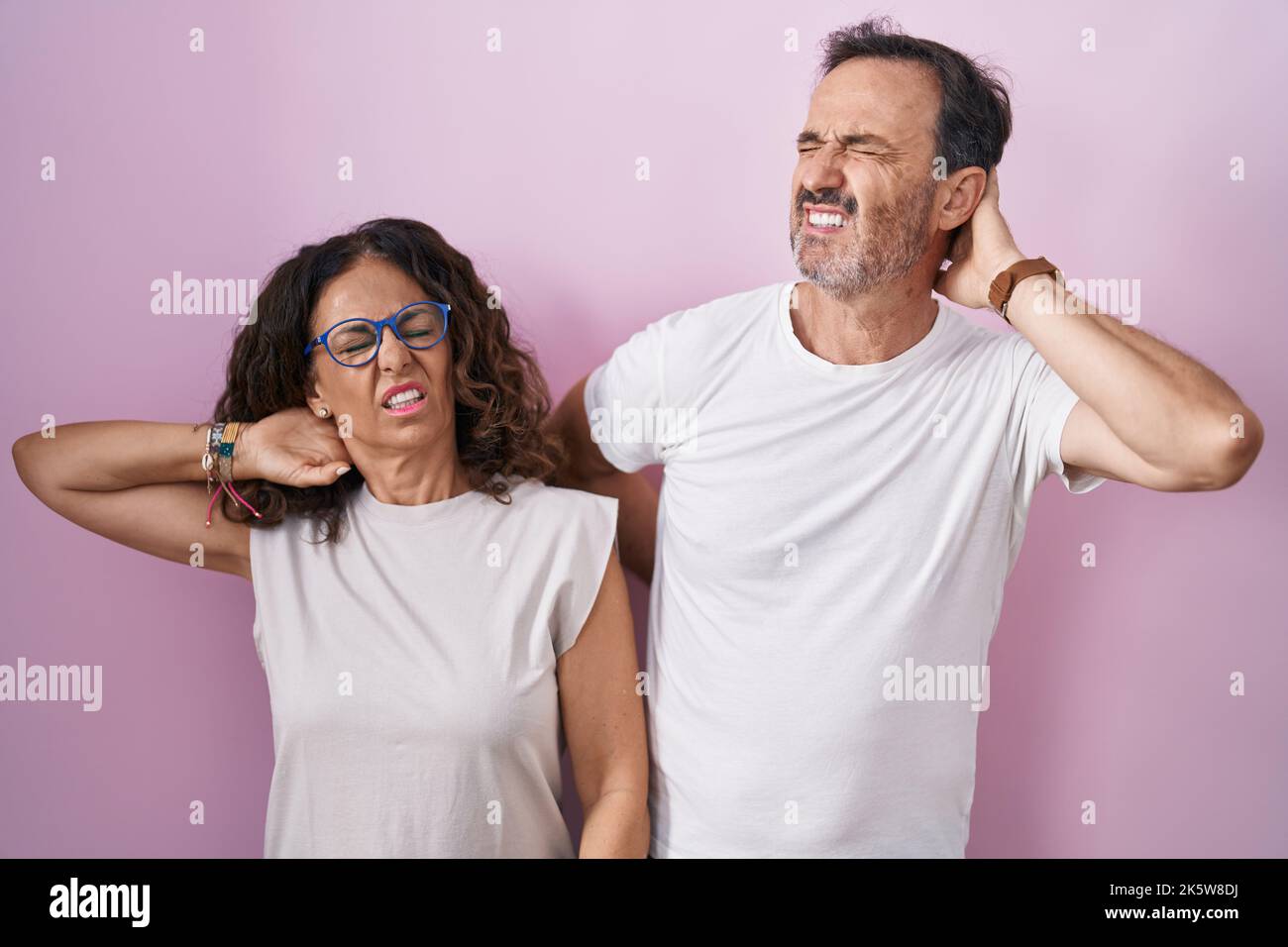 Middle age hispanic couple together over pink background suffering of ...