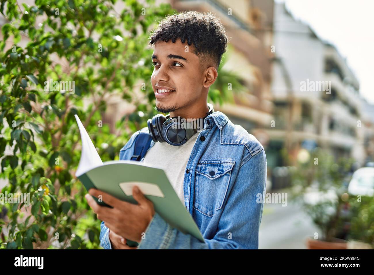 Hispanic young man reading a book at the street Stock Photo - Alamy