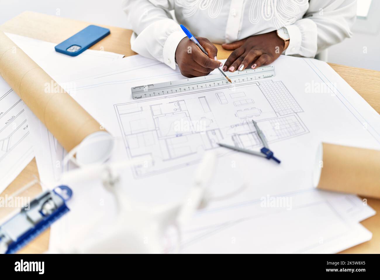 Young african american woman architect drawing on house plans at ...
