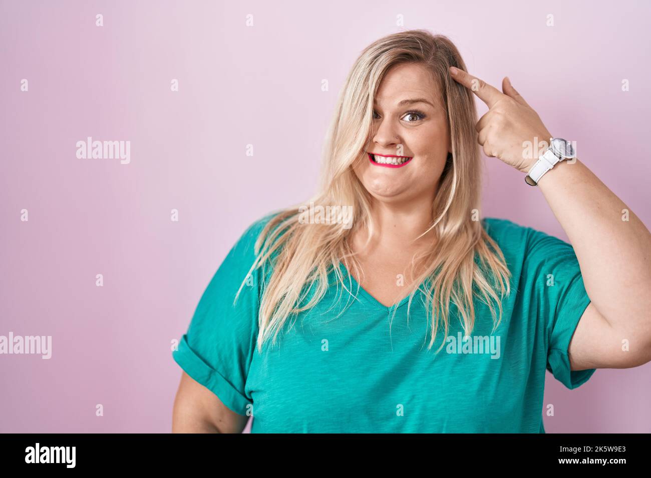 Caucasian plus size woman standing over pink background smiling ...