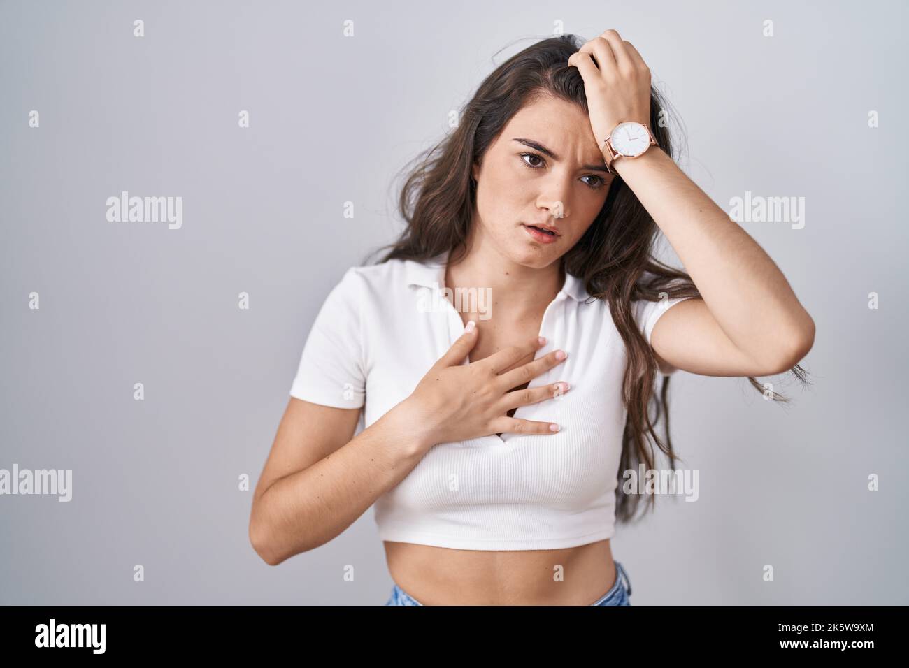 Young teenager girl standing over white background touching forehead ...