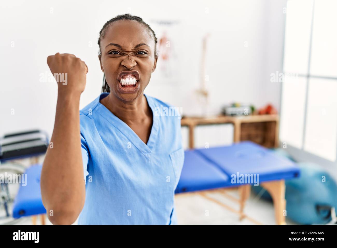 Black woman with braids working at pain recovery clinic angry and mad ...