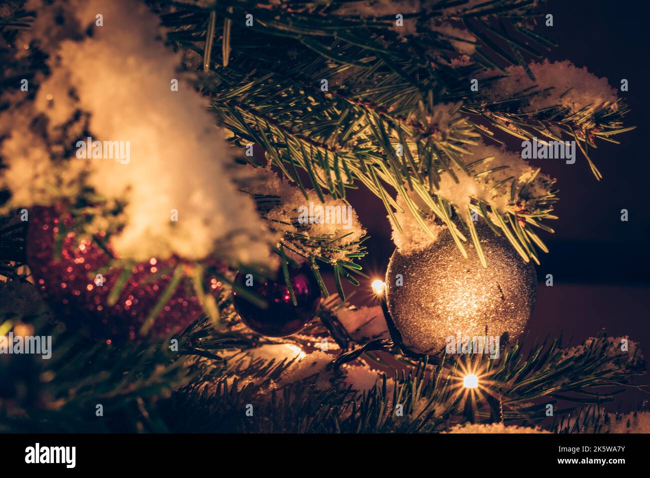 christmas baubles on the tree covered by snow with shining lights Stock ...