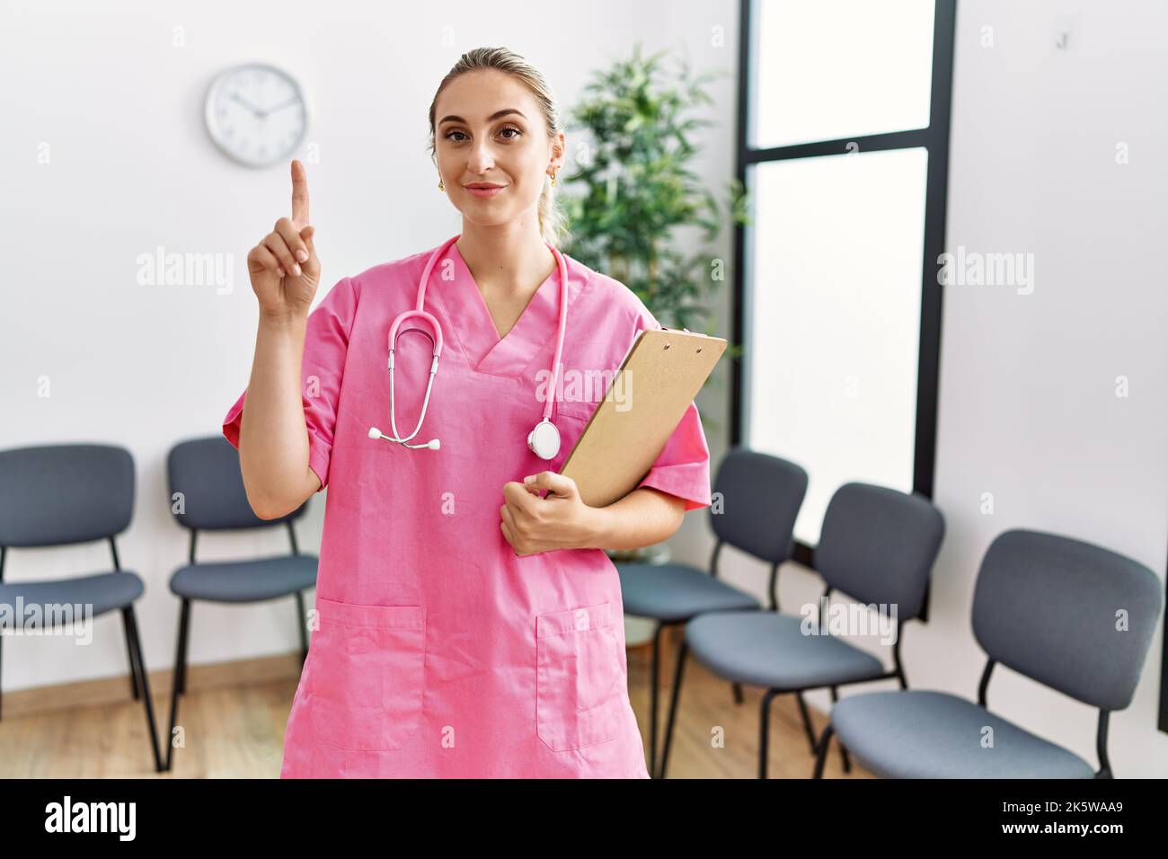 Young nurse woman at medical clinic waiting room surprised with an idea ...