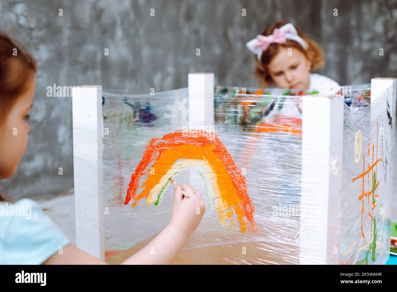 Two little girls learn to paint rainbow and nature. Having fun in kid ...