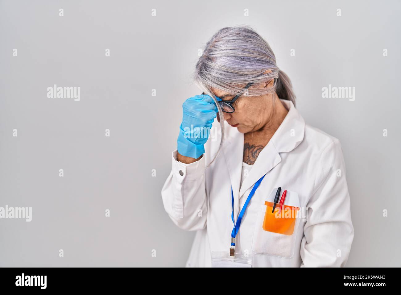 Middle age woman with grey hair wearing scientist robe tired rubbing ...