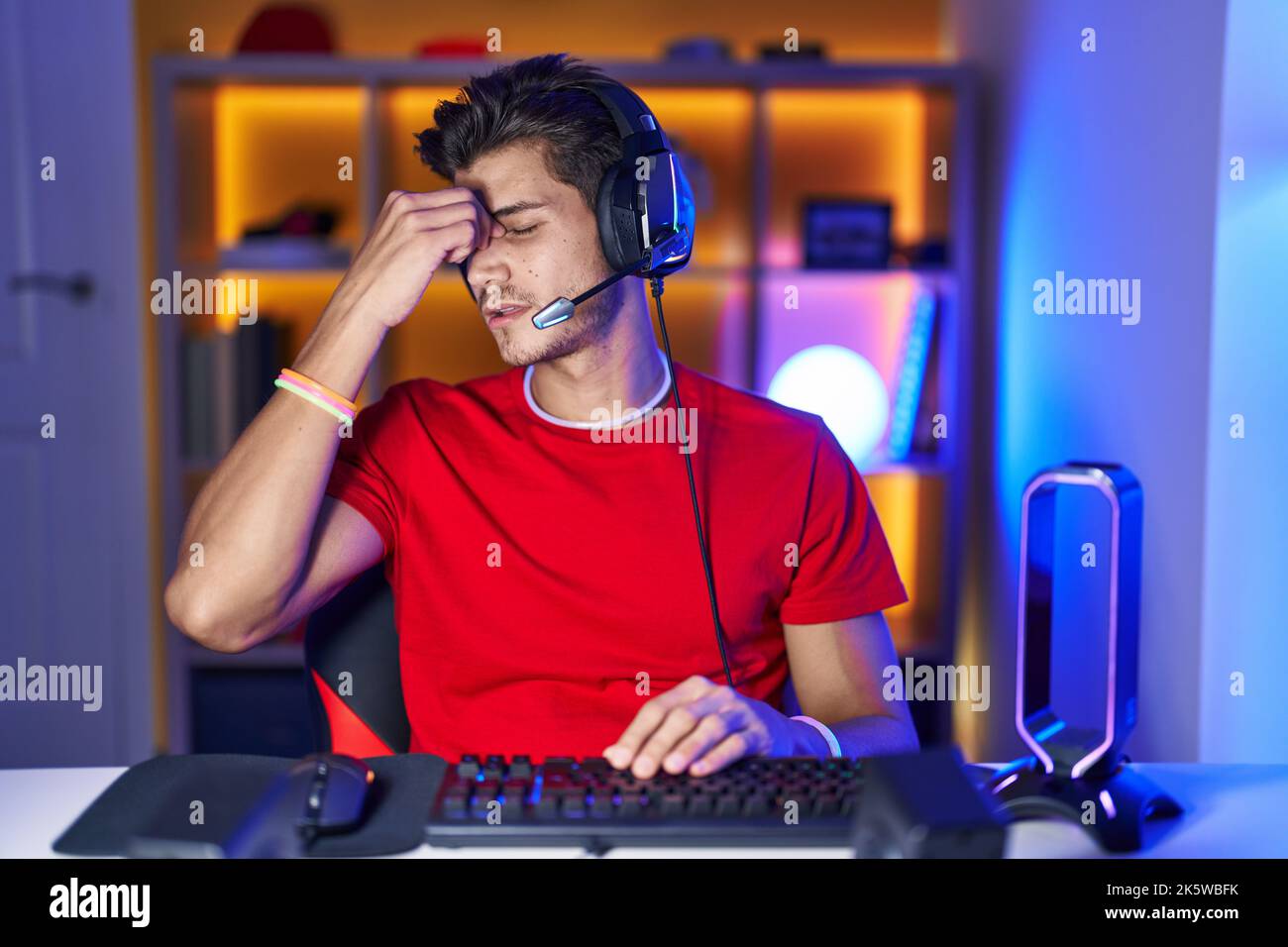Young hispanic man playing video games tired rubbing nose and eyes ...