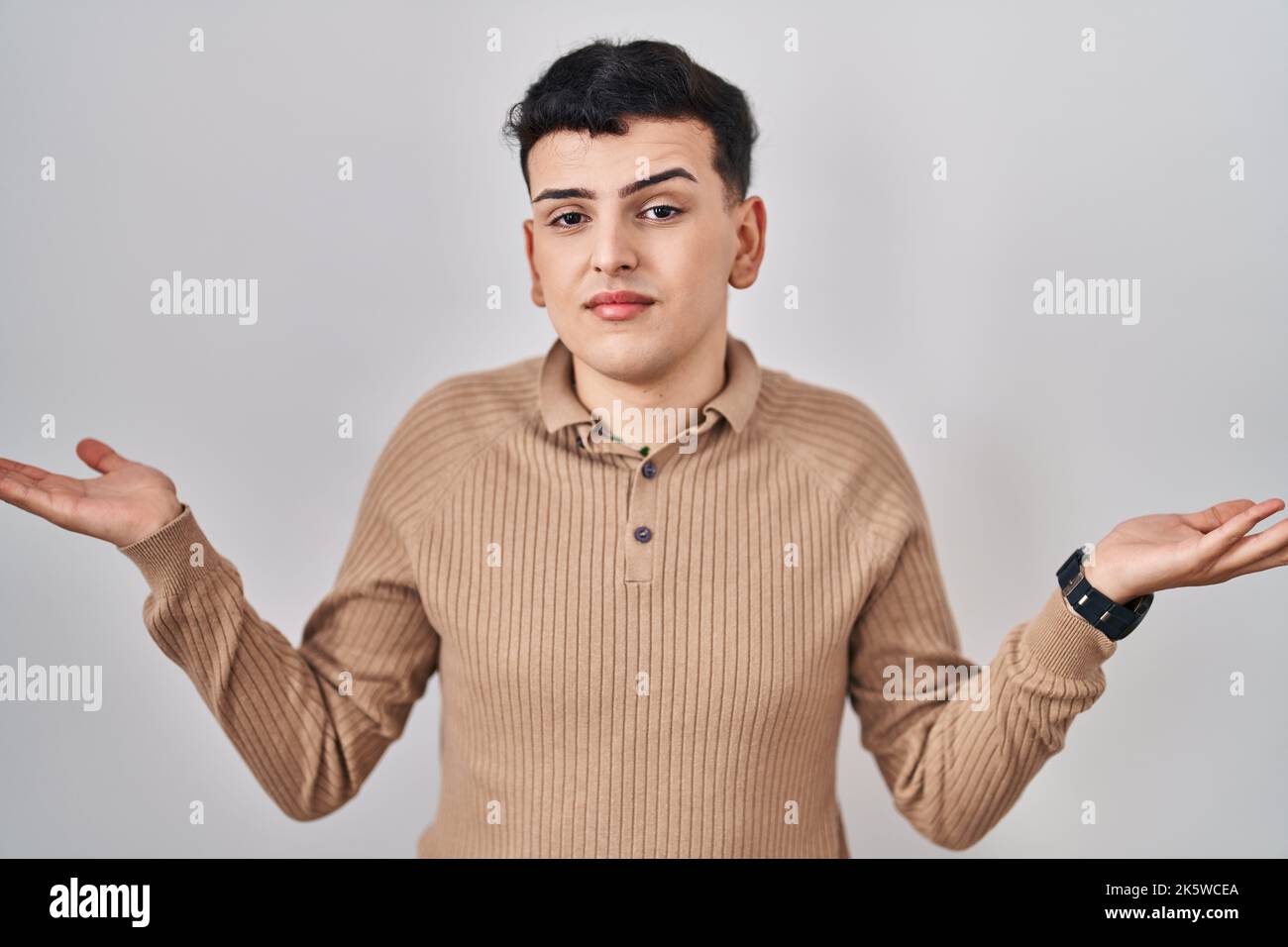 Non binary person standing over isolated background clueless and ...