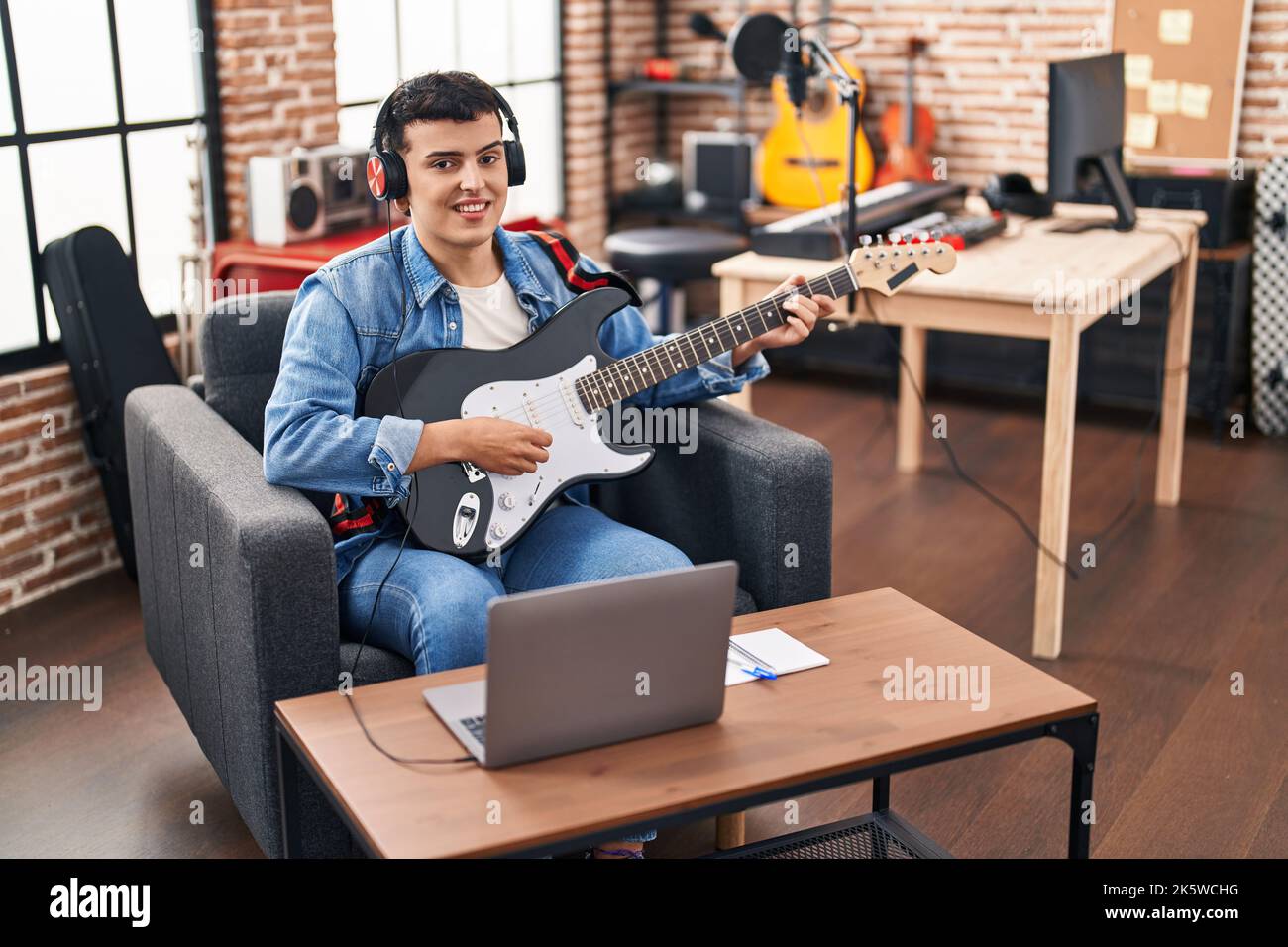 Young non binary man musician having online electric guitar lesson at ...