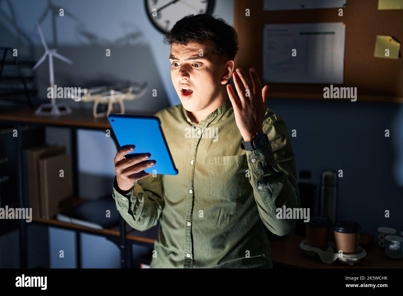 Non binary person using touchpad device at night crazy and scared with ...