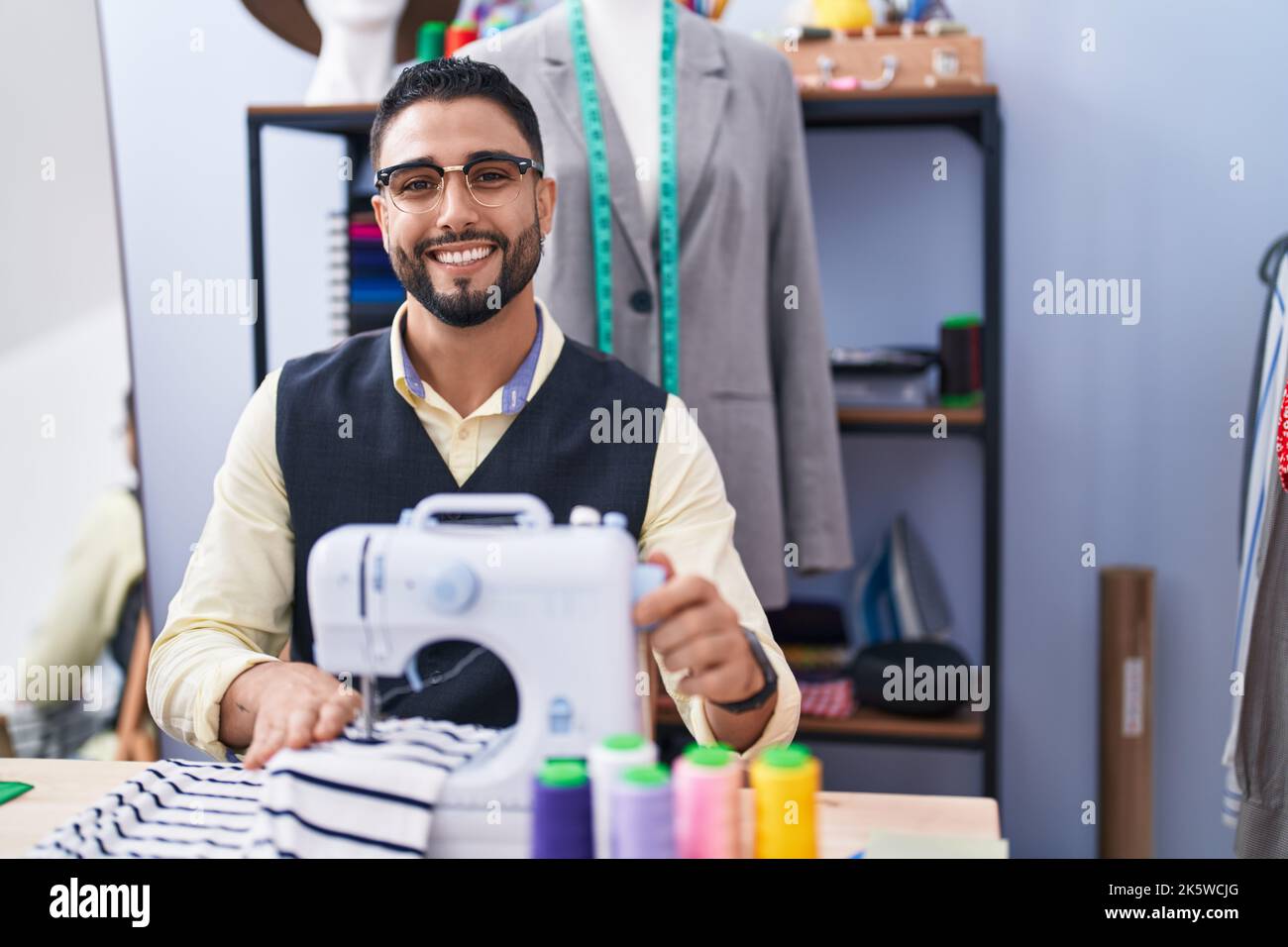 Young arab man tailor smiling confident using sewing machine at ...