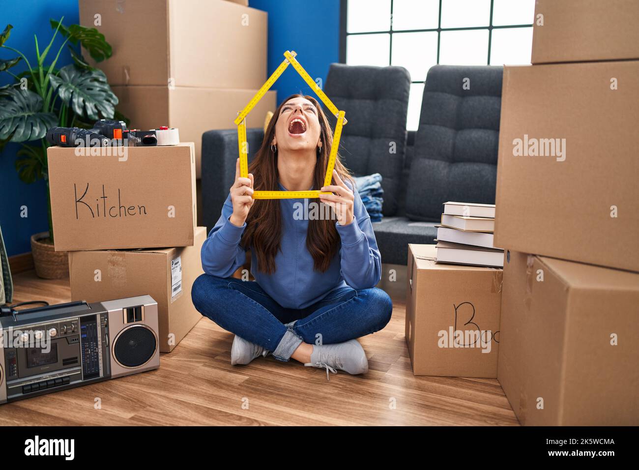 Young brunette woman sitting on the floor at new home angry and mad ...