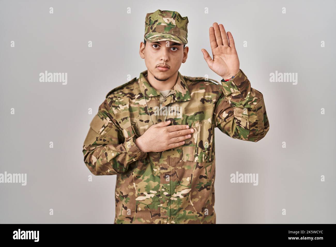 Young arab man wearing camouflage army uniform swearing with hand on ...