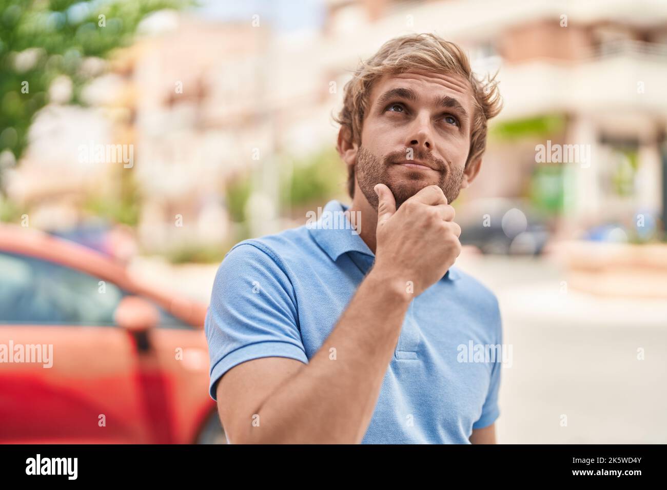 Young man standing with doubt expression at street Stock Photo - Alamy