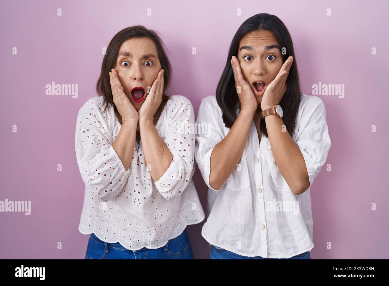 Hispanic mother and daughter together afraid and shocked, surprise and ...