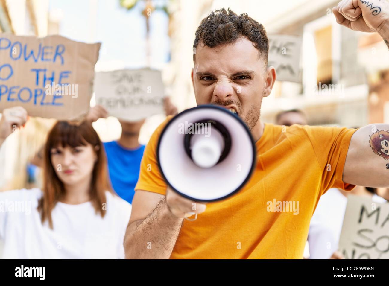 Group of young activists protesting holding banner and using megaphone ...
