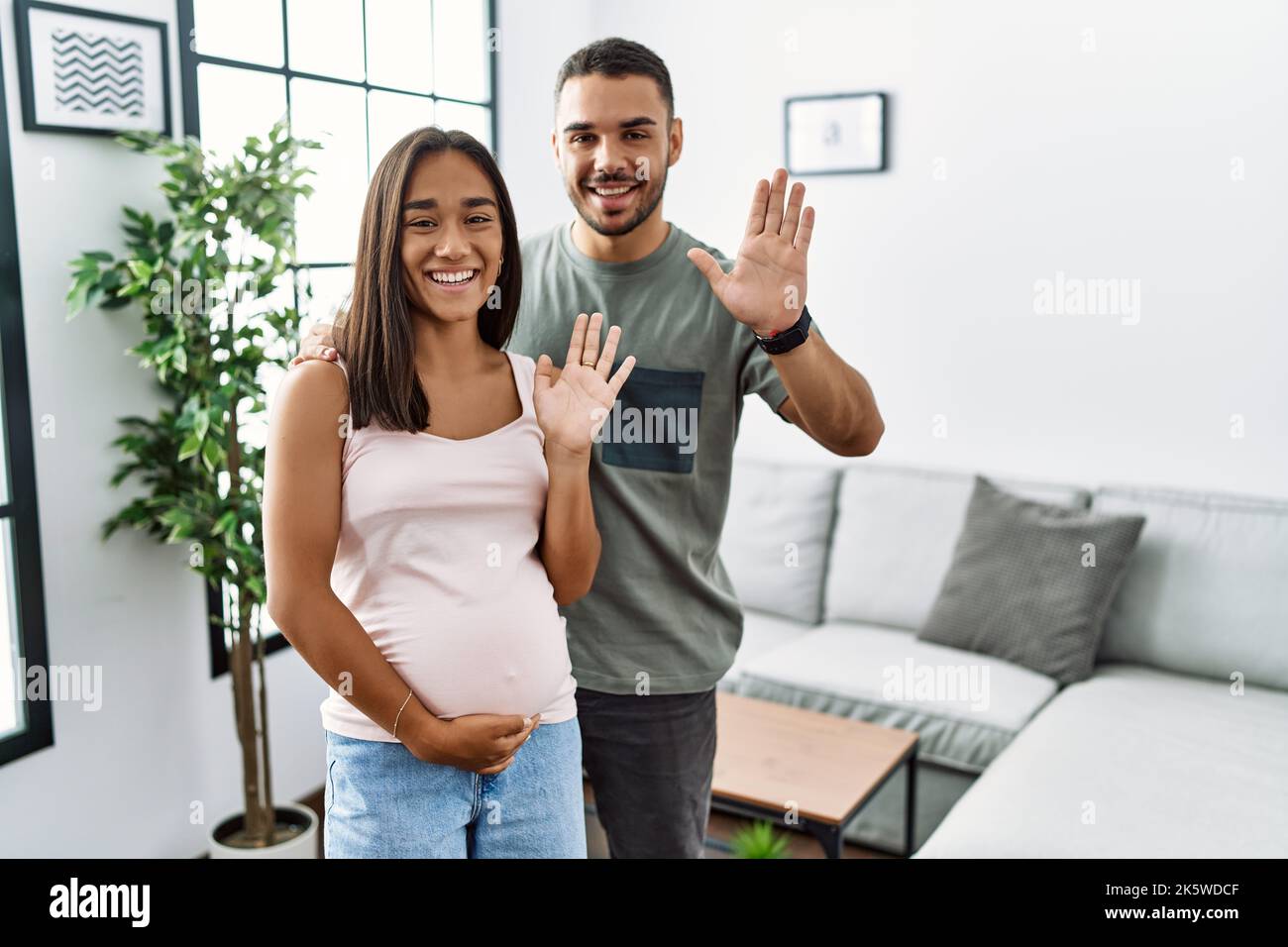 Young interracial couple expecting a baby, touching pregnant belly ...