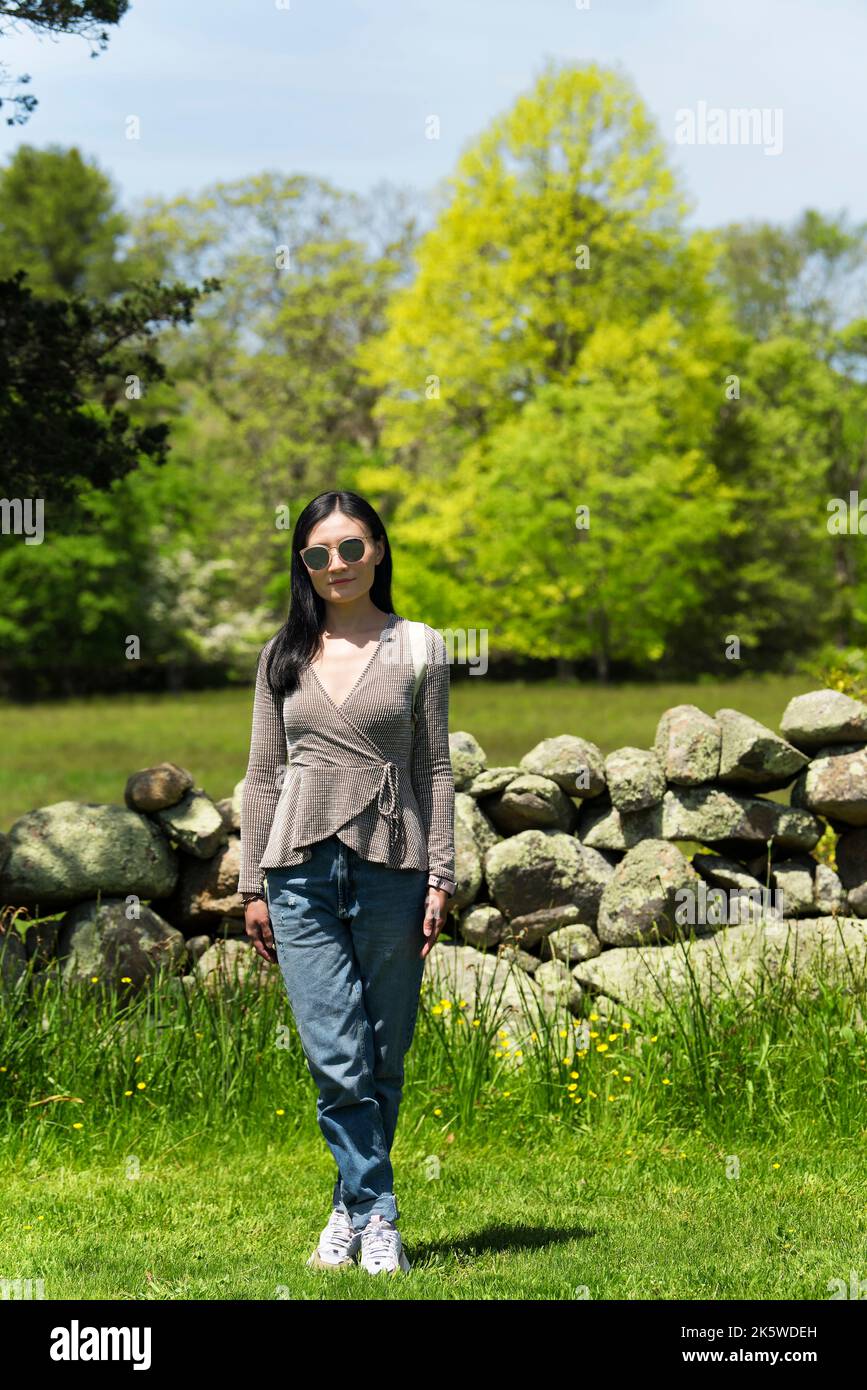 A Chinese Woman Standing Near A Rock Wall With Blurred Background At A