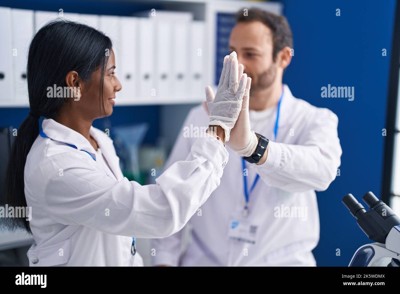 Man and woman scientists smiling confident high five at laboratory ...