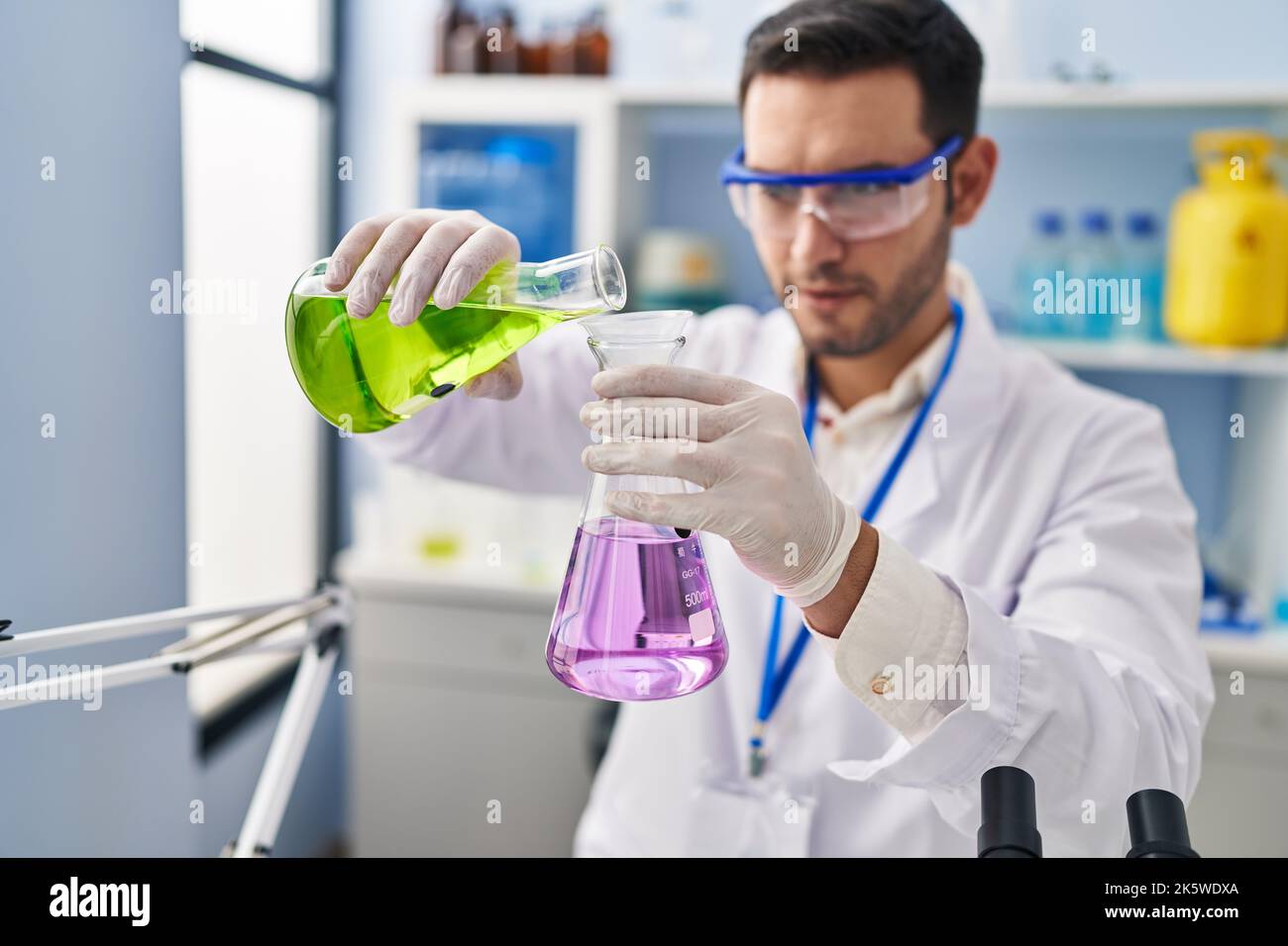 Young hispanic man scientist measuring liquid at laboratory Stock Photo ...