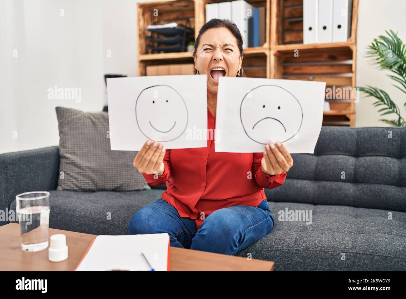 Middle age hispanic woman working on depression holding sad to happy ...