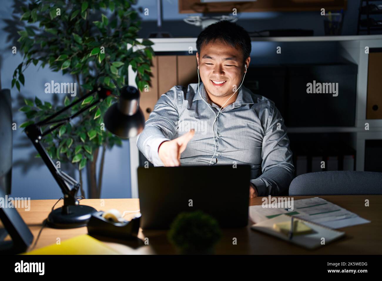 Young chinese man working using computer laptop at night smiling ...