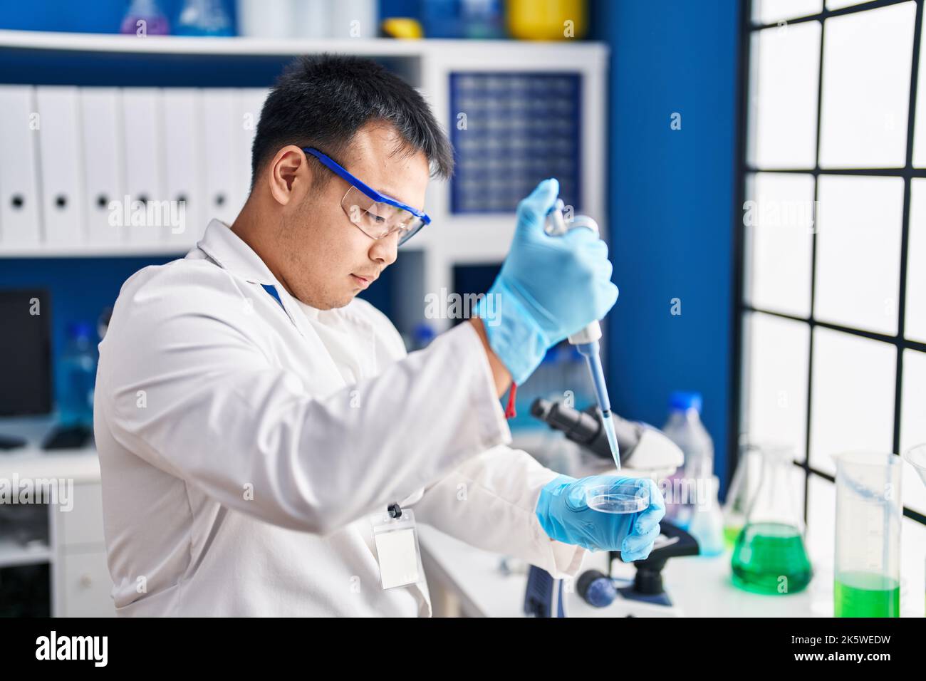 Young chinese man wearing scientist uniform working at laboratory Stock ...