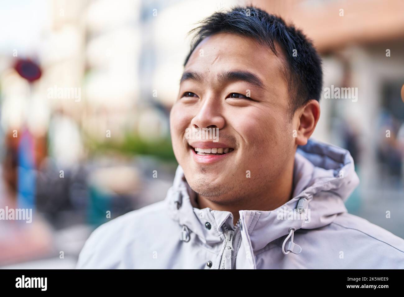Young chinese man smiling confident standing at street Stock Photo - Alamy