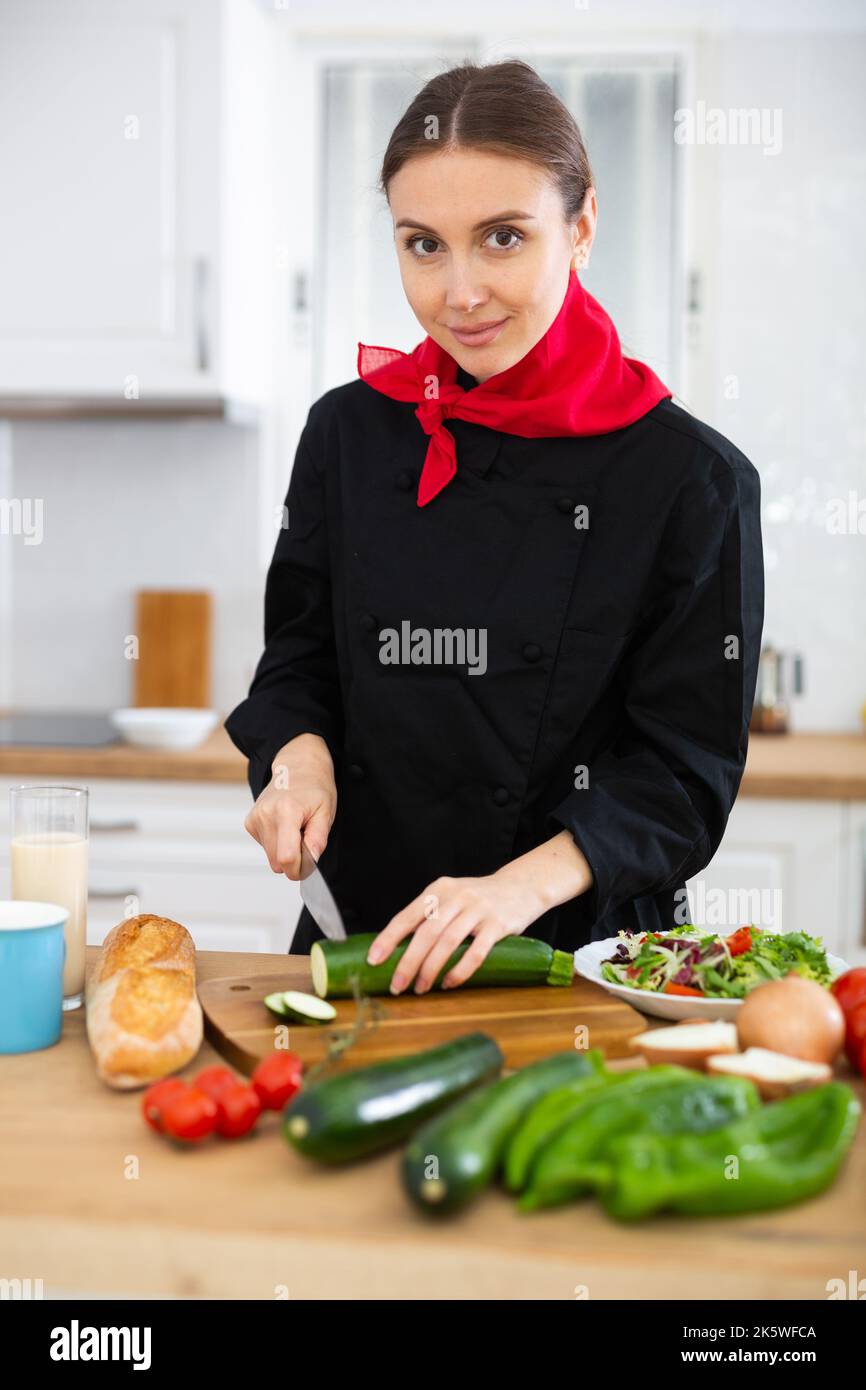 Female cook in black uniform chopping vegetables in kitchen Stock Photo ...
