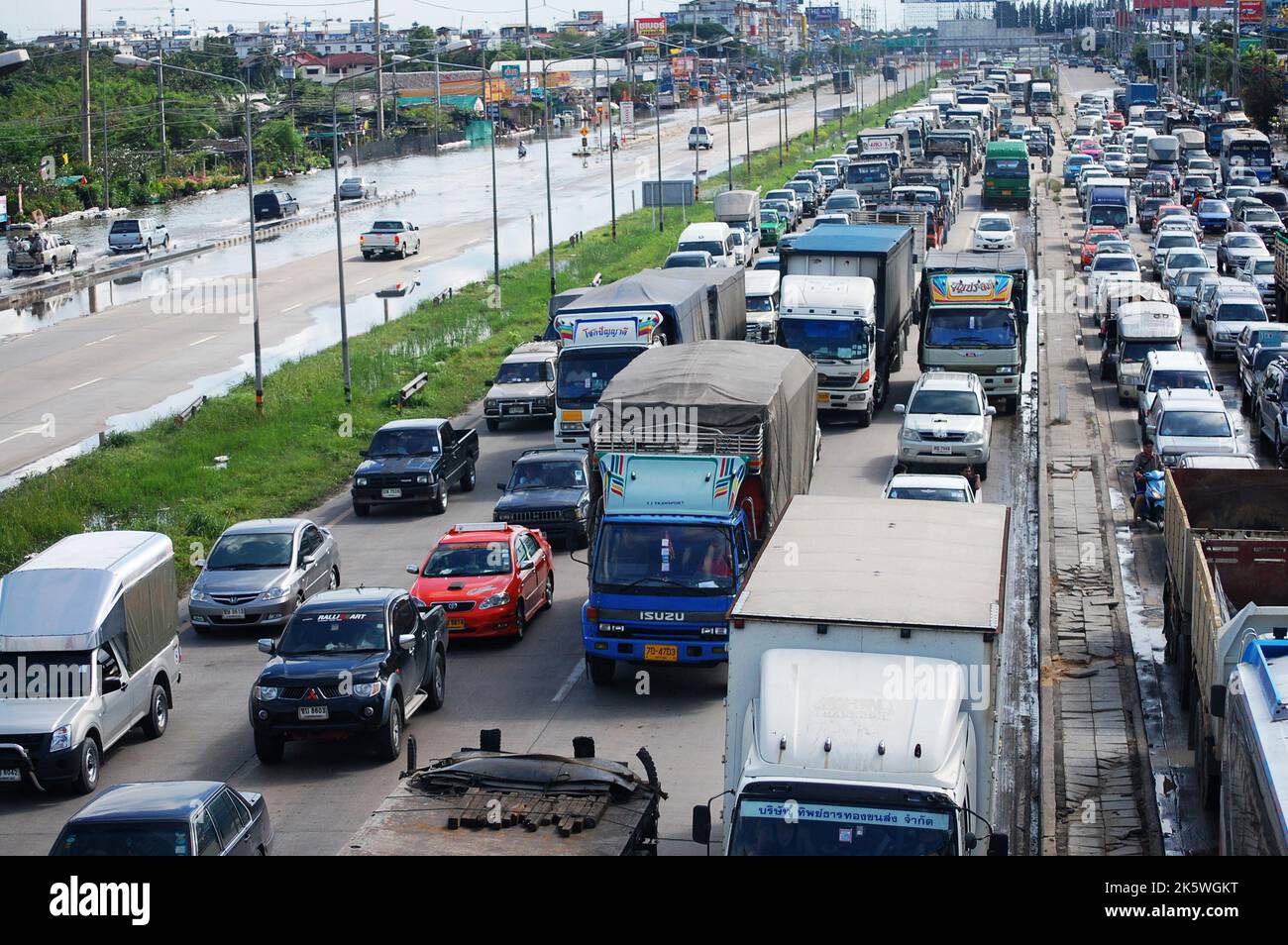Thai people riding motorcycle and driving car on street while water ...