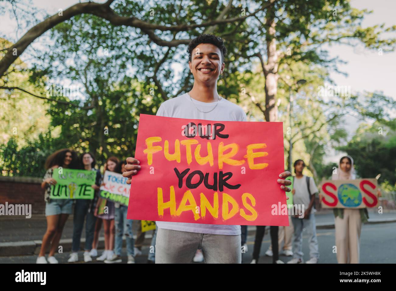 Happy teenage boy smiling at the camera while holding a banner sign ...