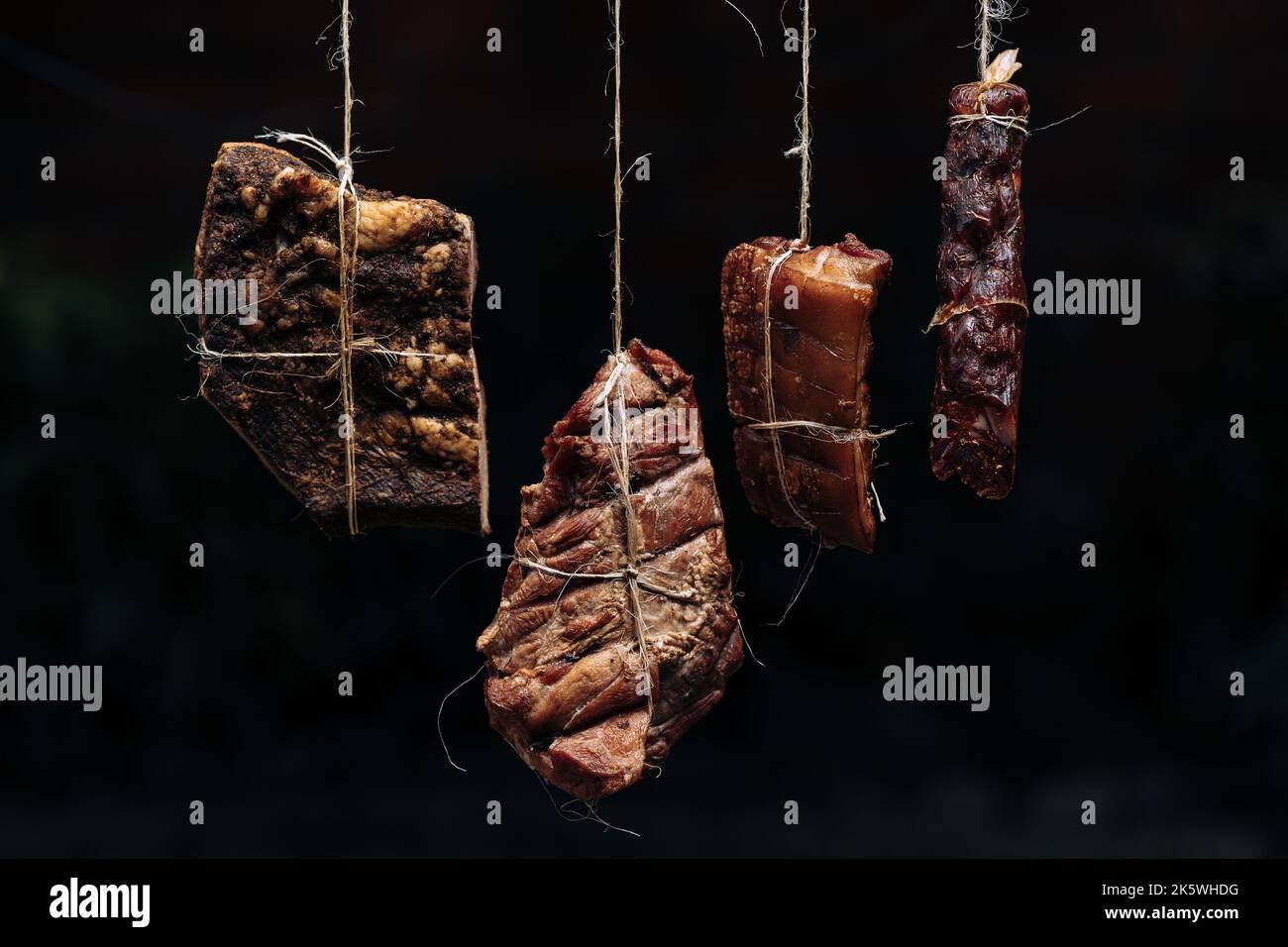 Dried meat pieces hanging by a thread on a black background Stock Photo ...