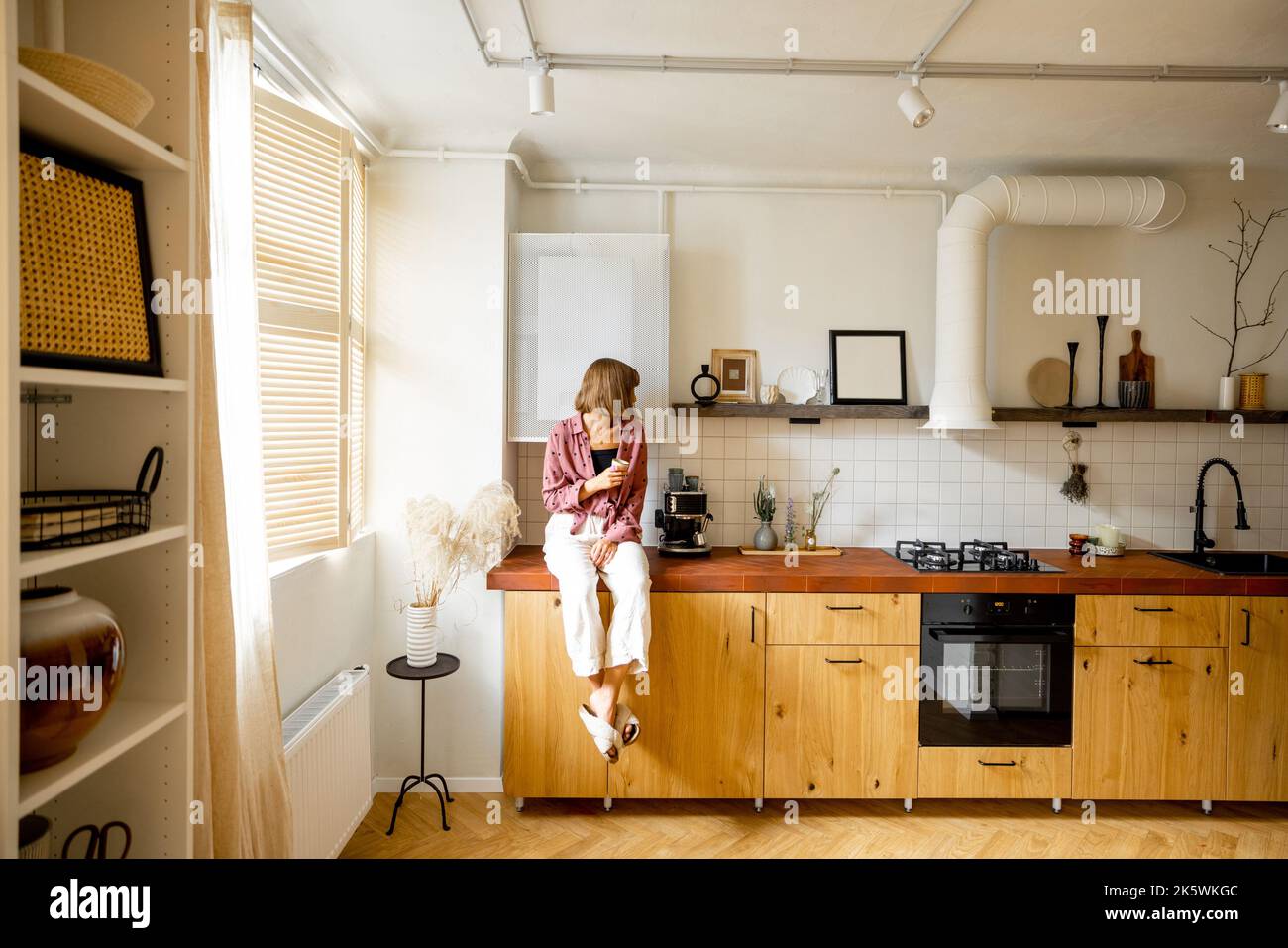 Modern kitchen interior with person sitting on table top Stock Photo ...