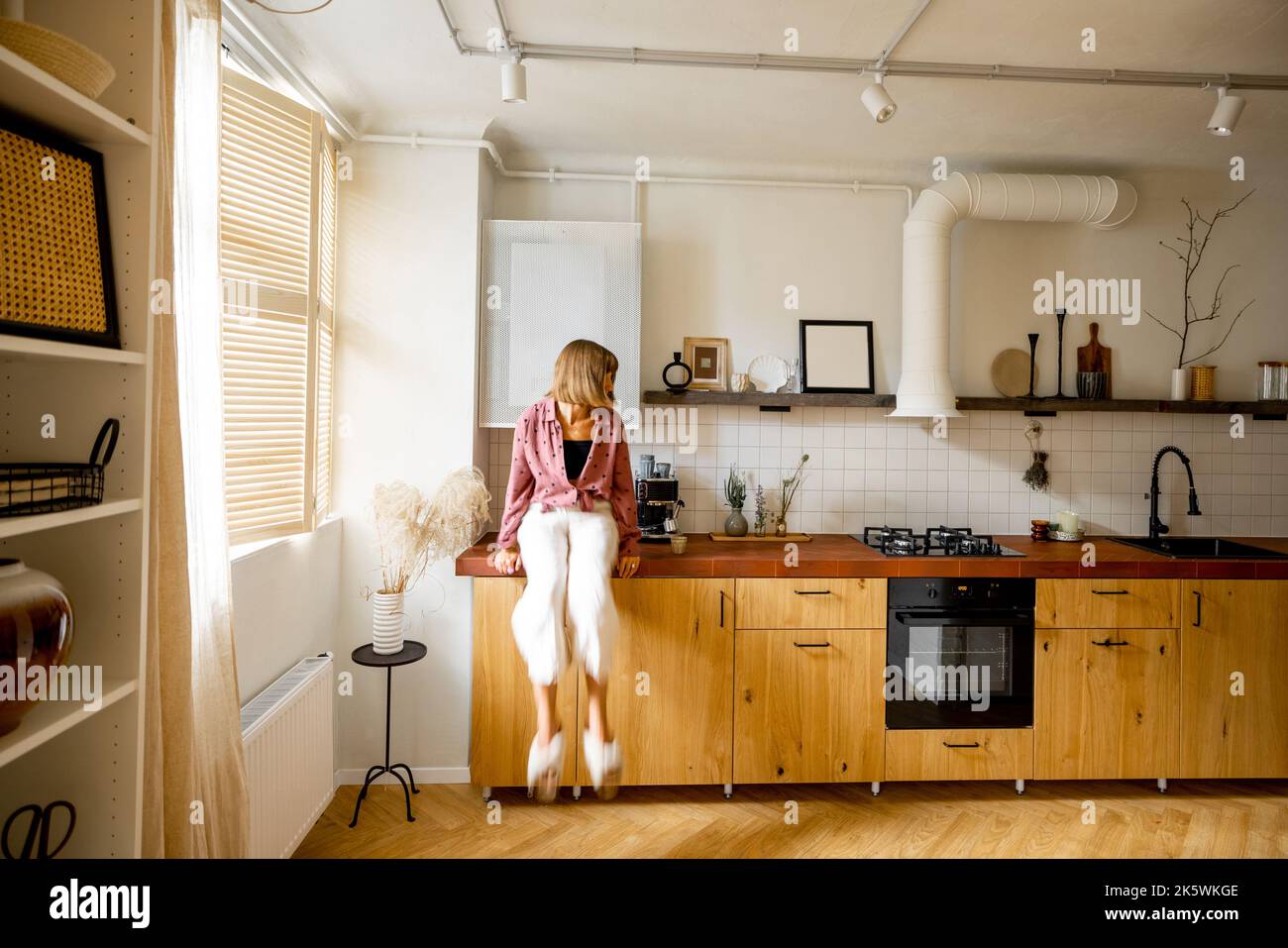 Modern kitchen interior with person sitting on table top Stock Photo ...